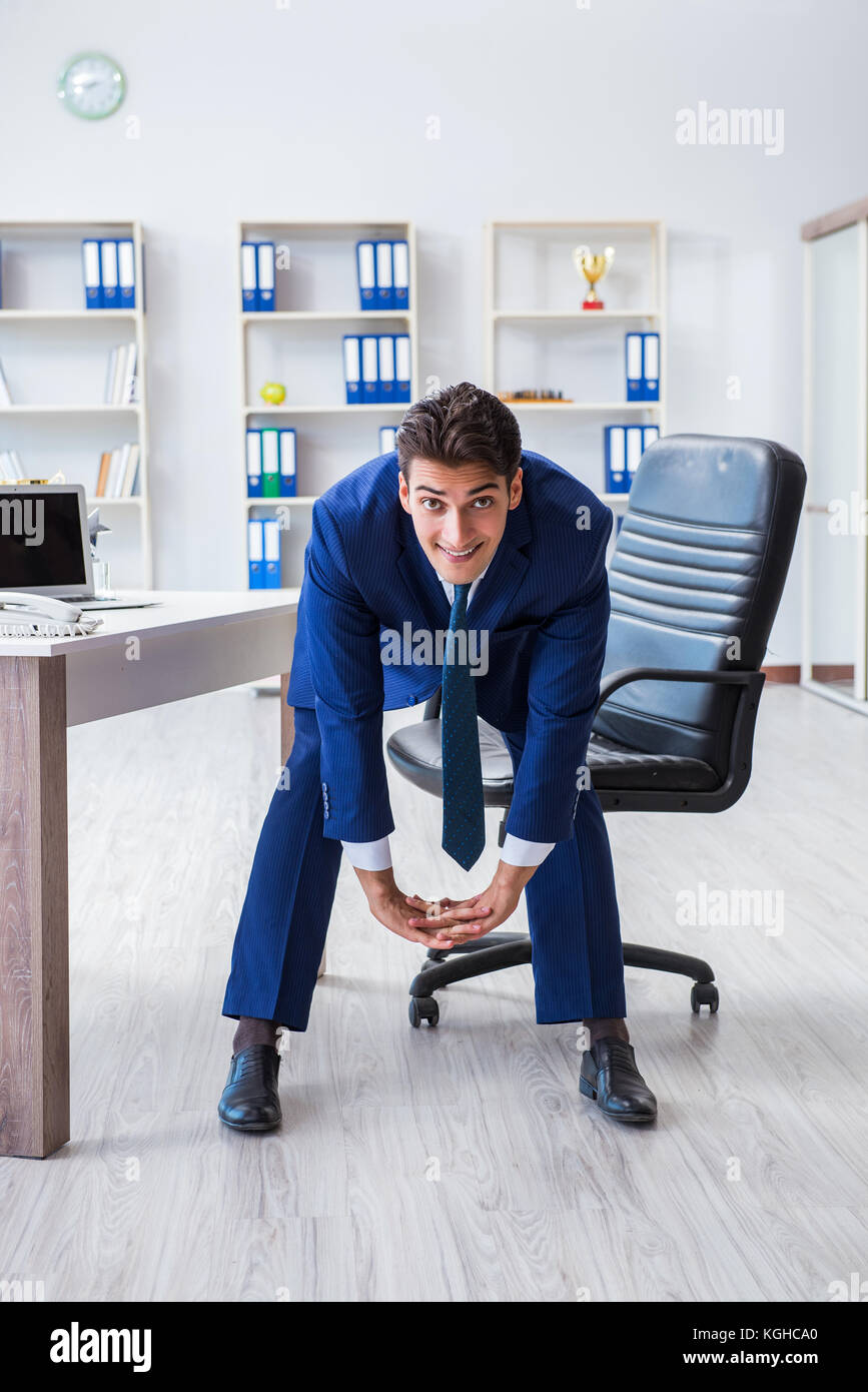 Young businessman doing sports stretching at workplace Stock Photo - Alamy