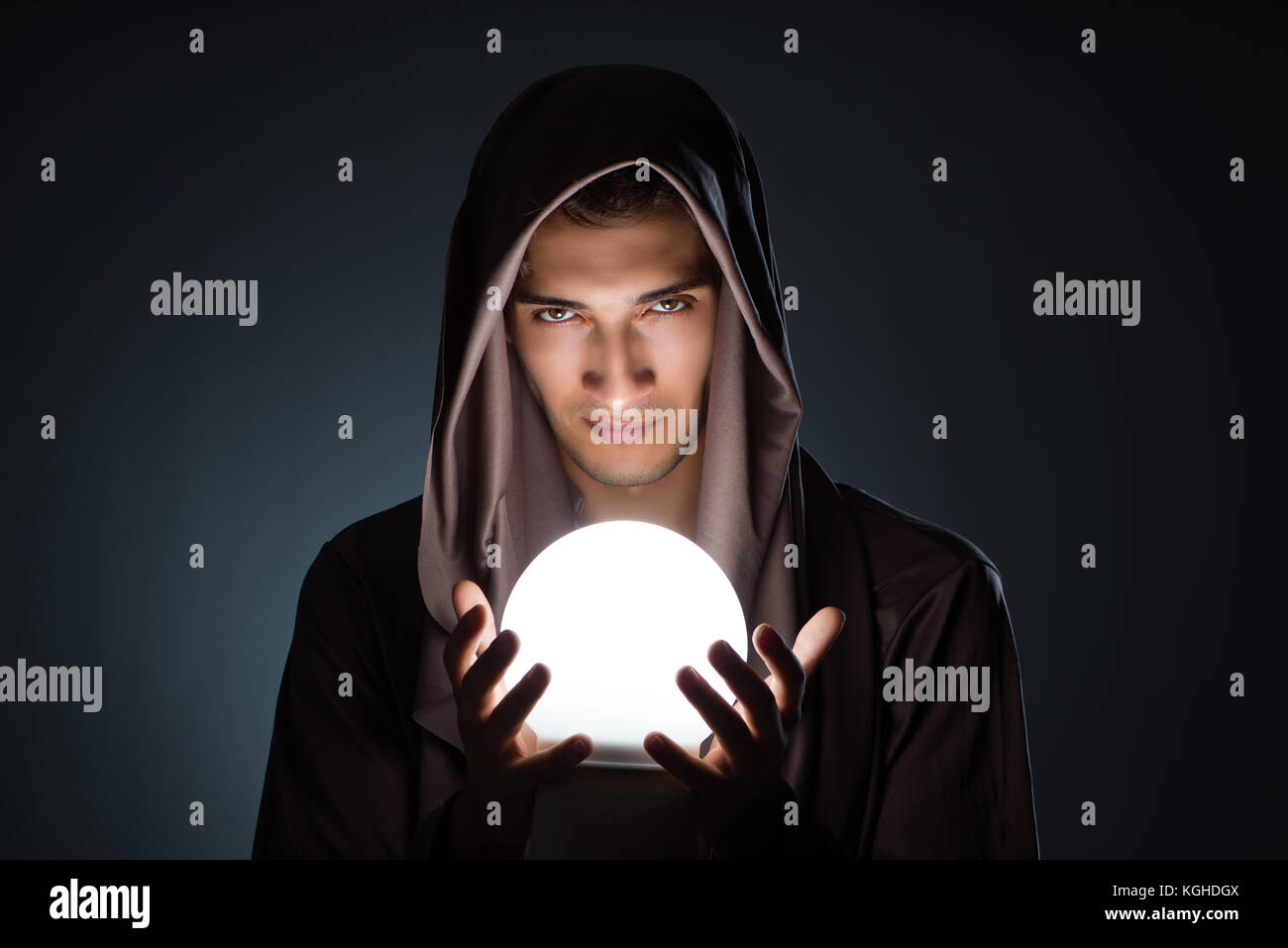 Young wizard with crystal ball in dark room Stock Photo - Alamy