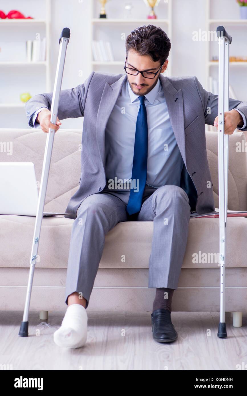 Businessman with crutches and broken leg at home working Stock Photo ...