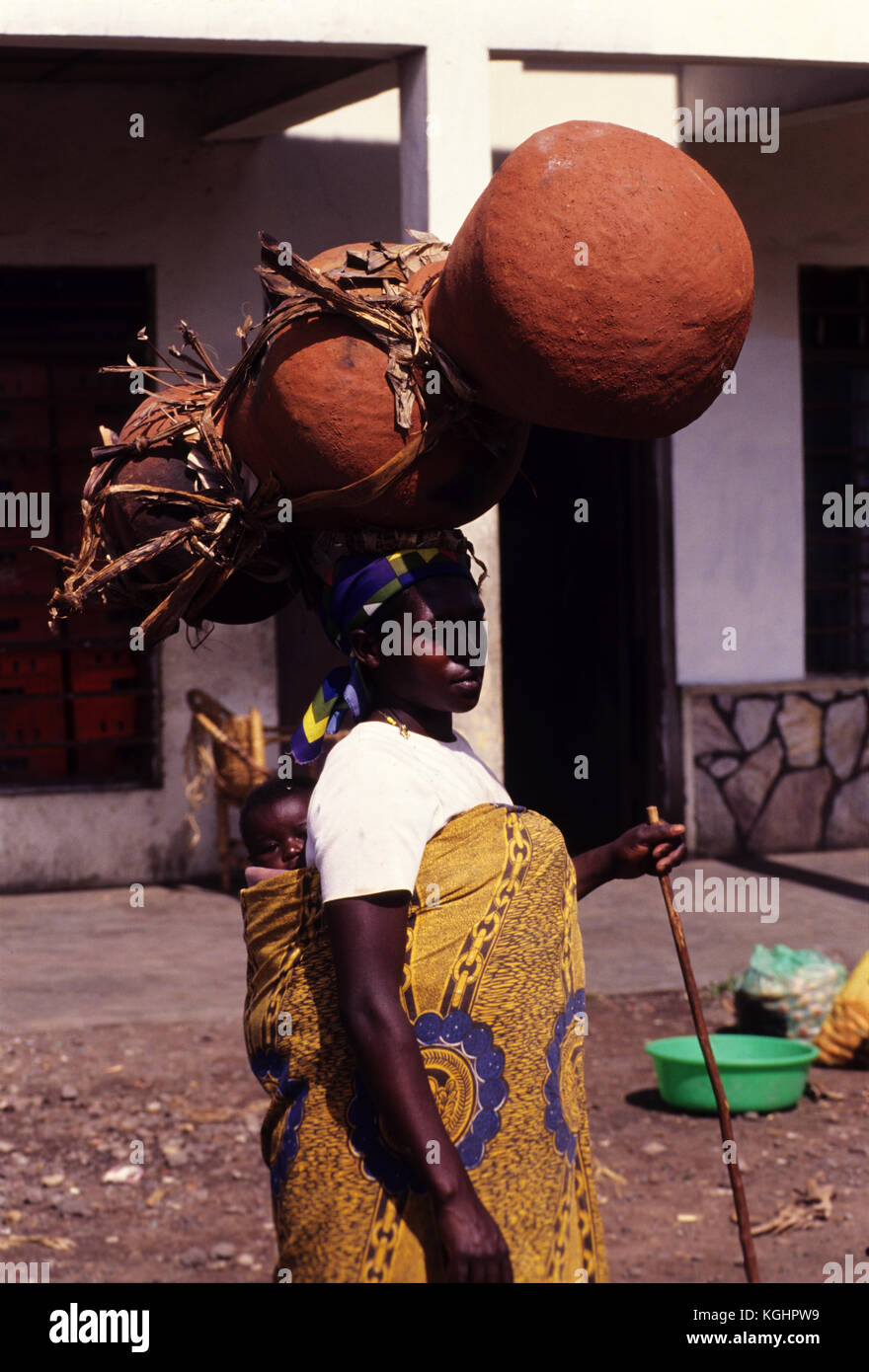 African woman carrying a baby on his back and a heavy load on his head ...