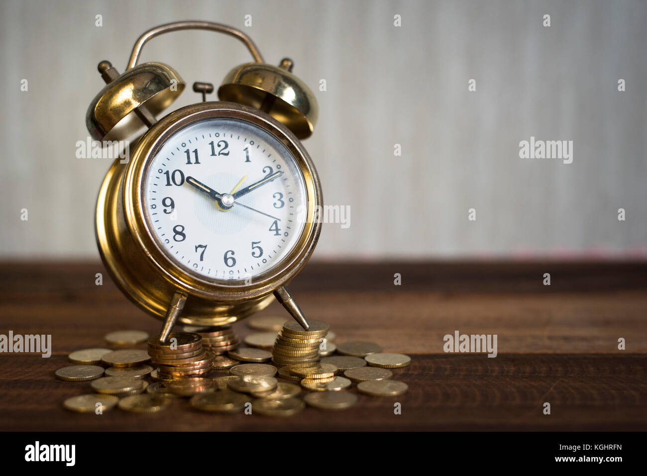 Time is precious concept - golden bell clock with coins on a wooden ...