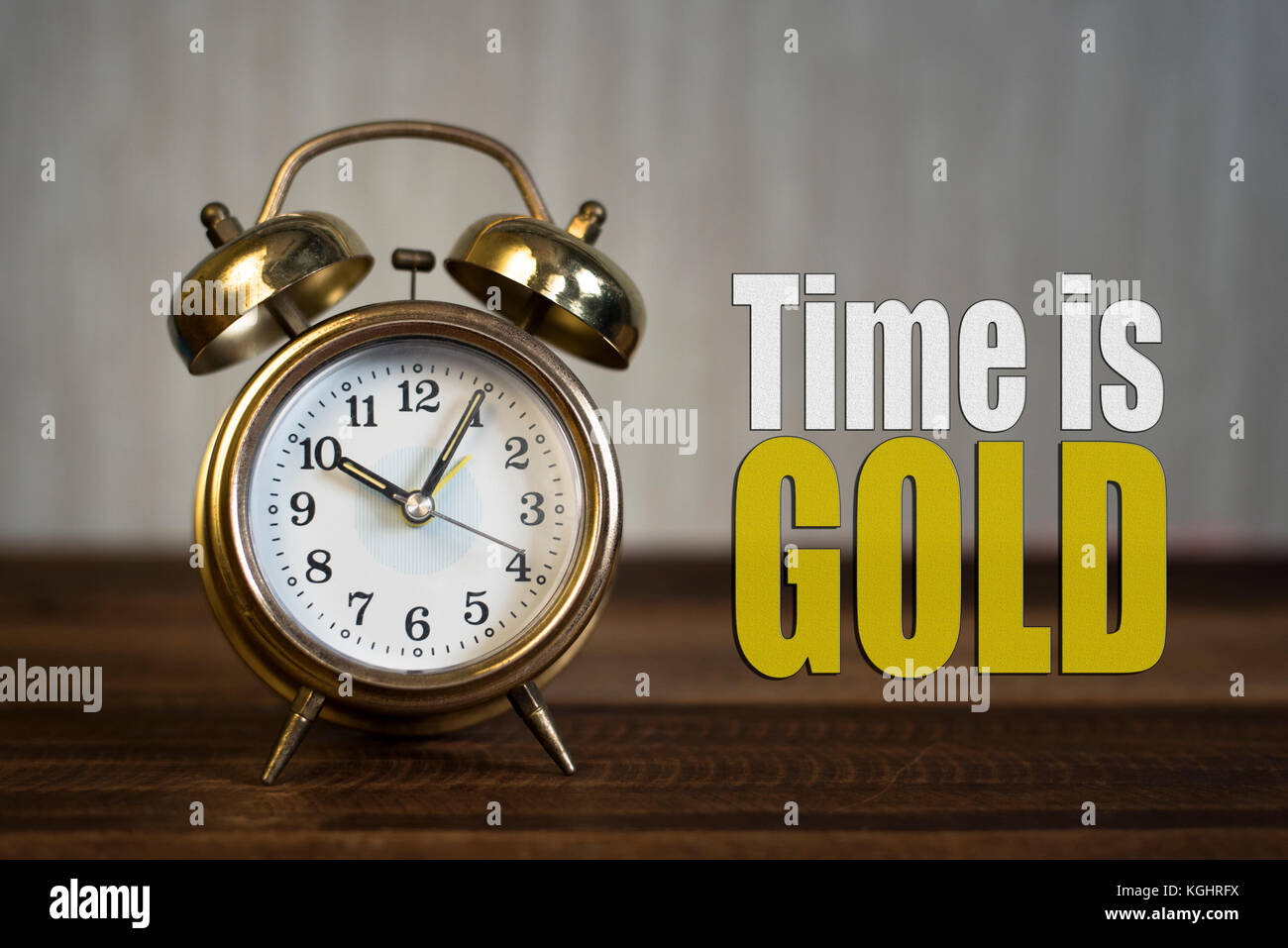 Time is gold concept - gold bell clock on a wooden table with "time is ...