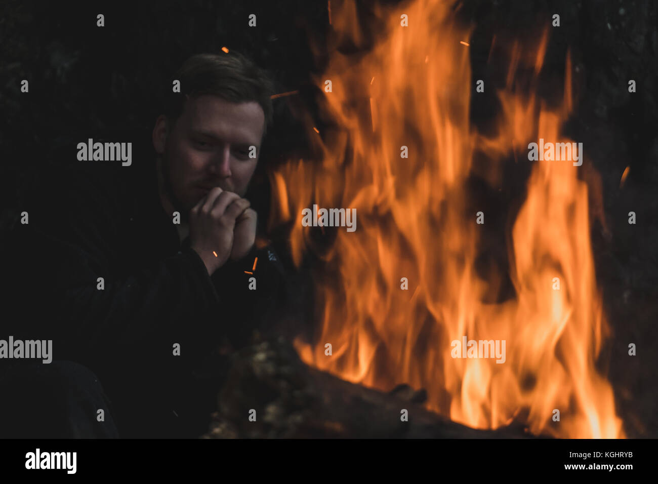 a man with a beard looks at the fire near the cave Stock Photo - Alamy