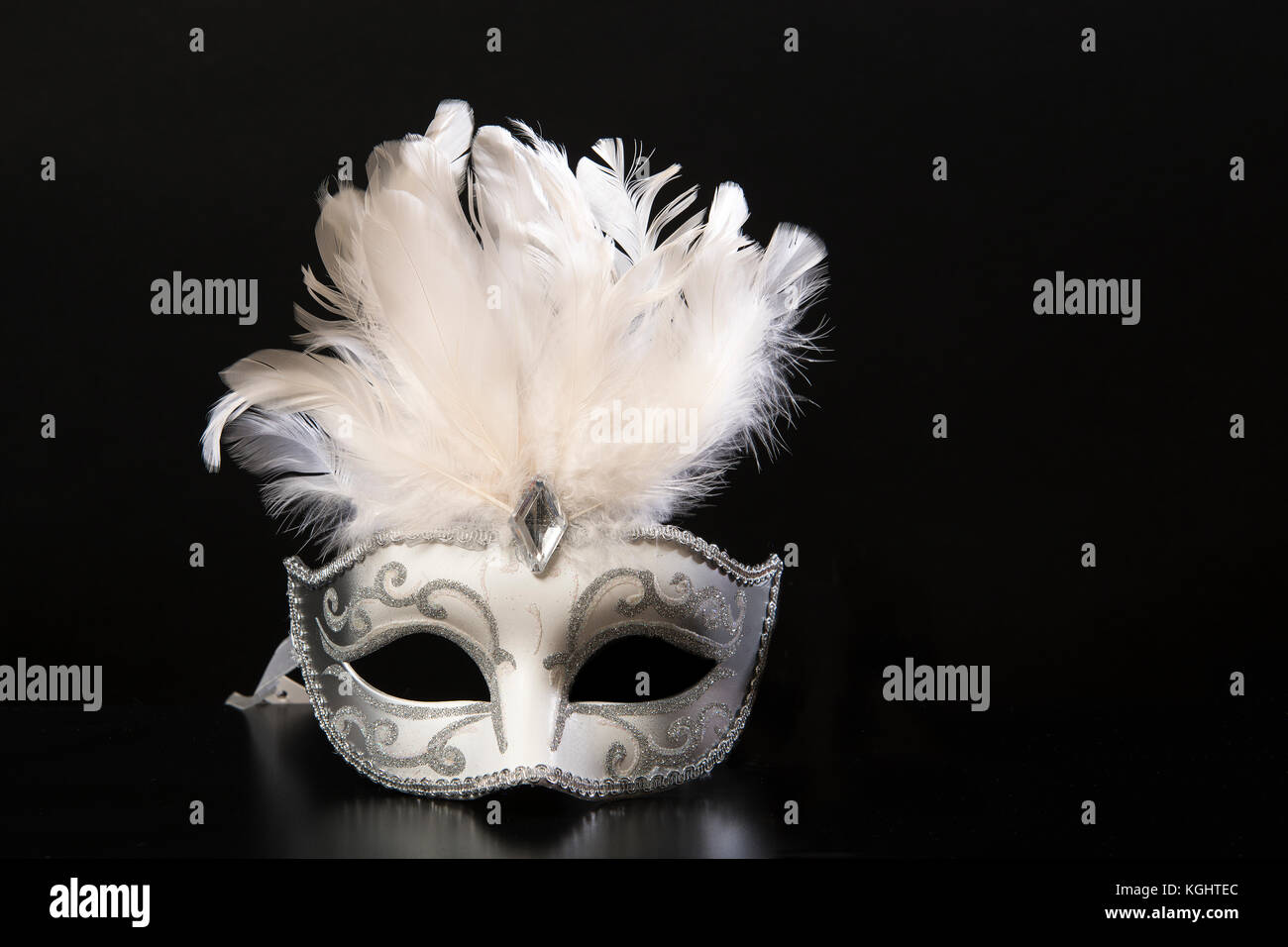 Pretty white and silver venetian carnival mask with feathers on a black ...