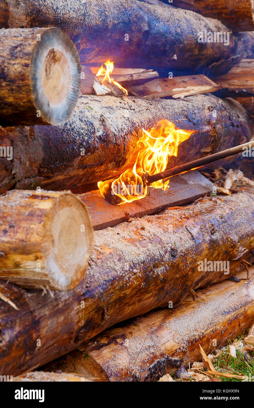 setting big bonfire made of logs on fire with torch Stock Photo - Alamy