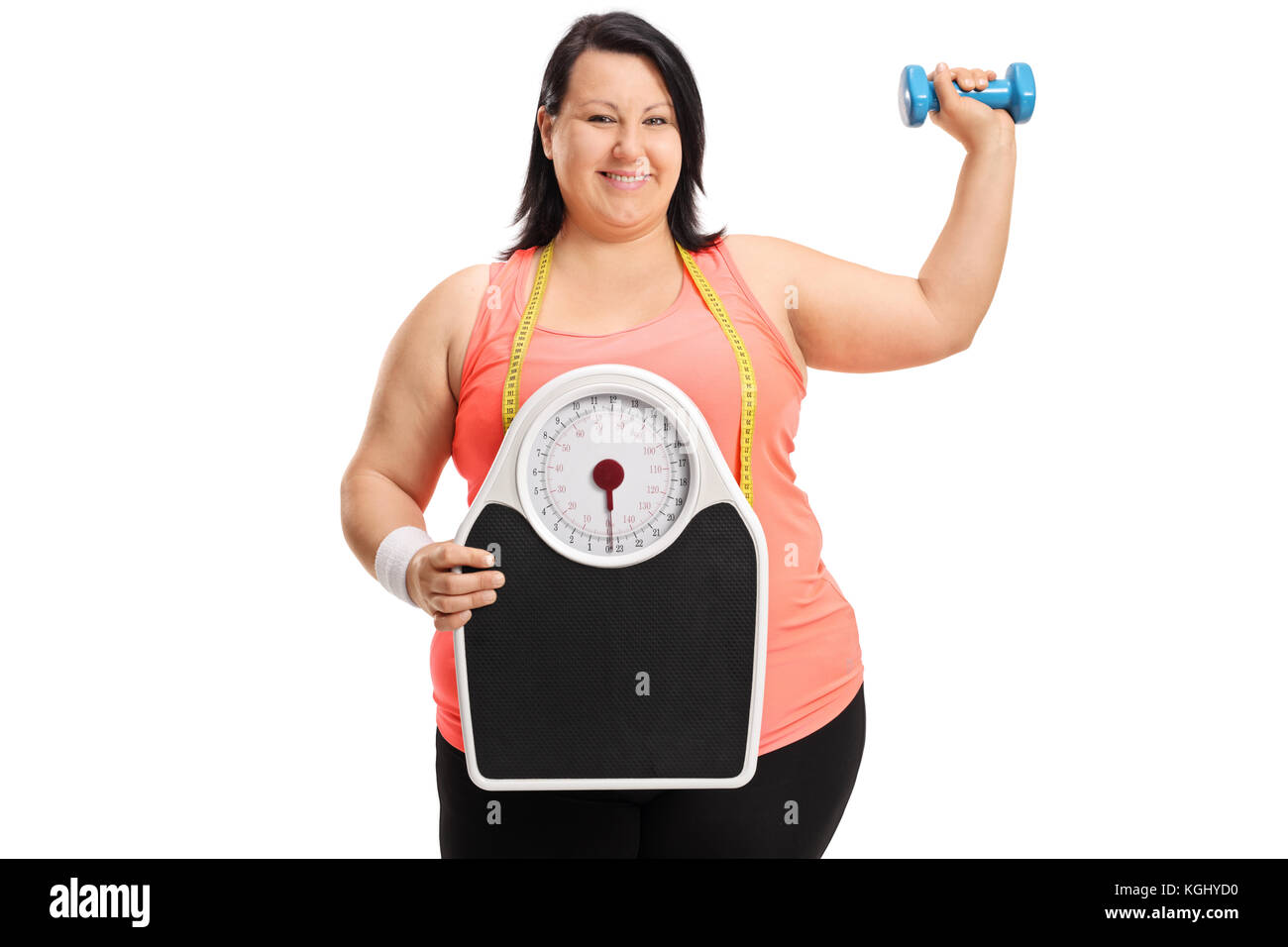 Joyful overweight woman with a weight scale and a small dumbbell ...
