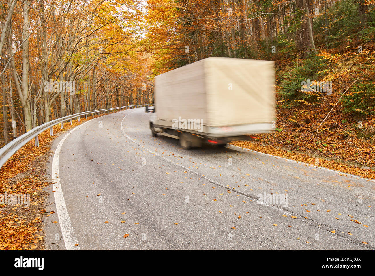 A van speeding on a road through colorful forest Stock Photo - Alamy