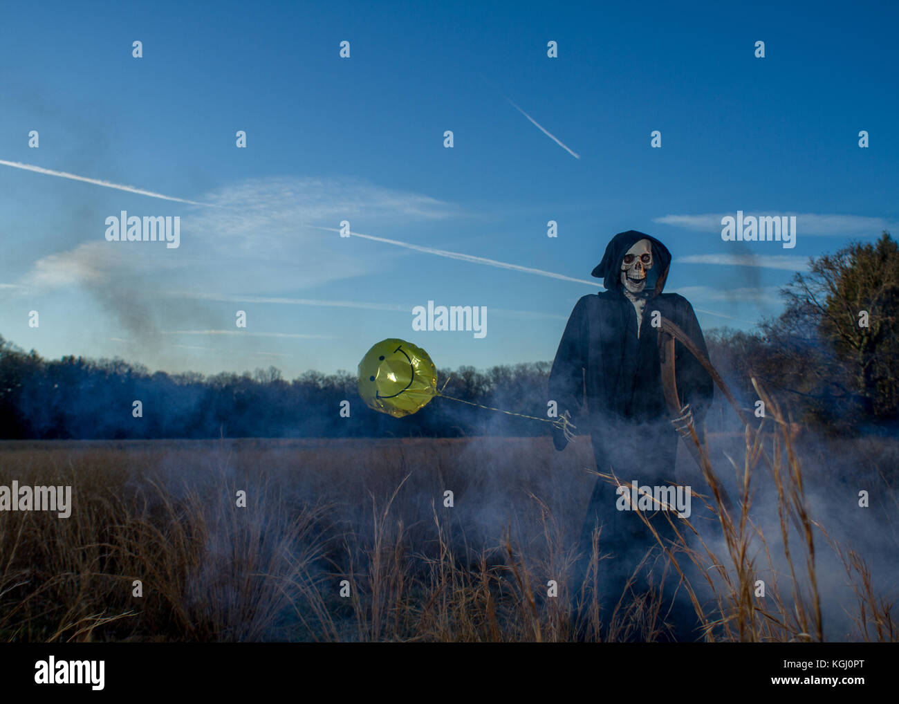 A grim Reaper standing in a field holding a smiley face balloon Stock ...
