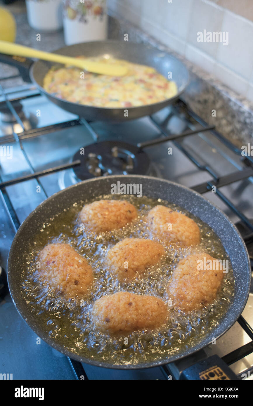 sicilian rice croquettes frying in pan with boiling oil Stock Photo - Alamy