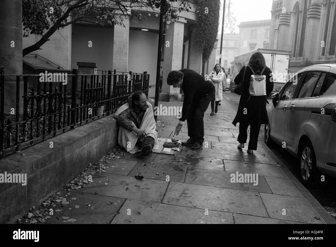 A man stops to drop some change into a hat of a homeless man begging on ...