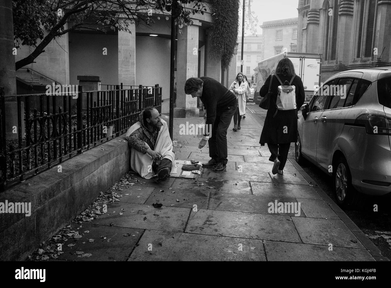 A man stops to drop some change into a hat of a homeless man begging on ...