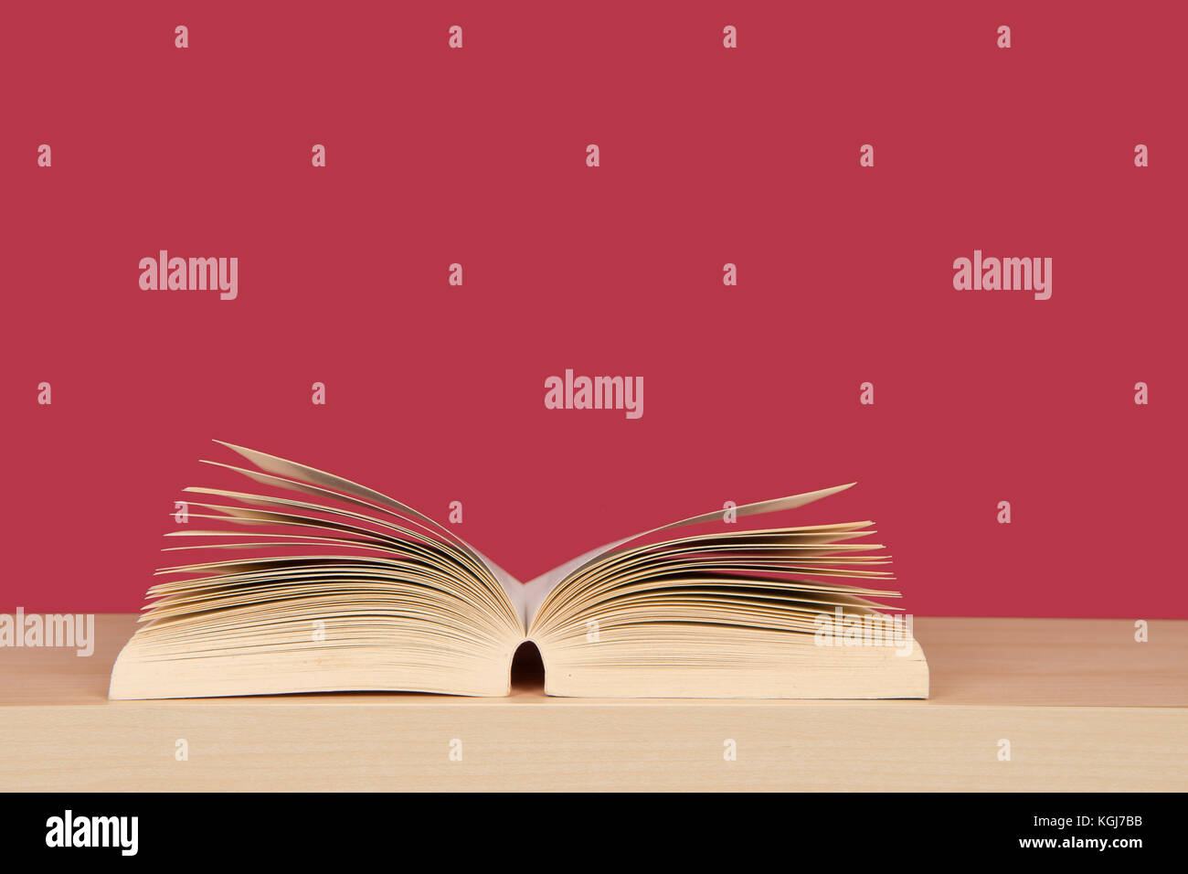 Open book with pages standing up lying on a bookplank on a red ...