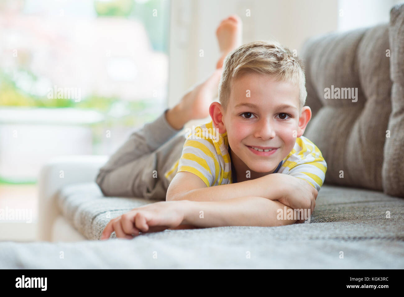 Happy schoolboy 9 years old lying on sofa at home Stock Photo - Alamy