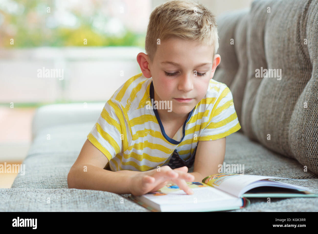 Portrait of clever little boy with reading book on the sofa Stock Photo ...