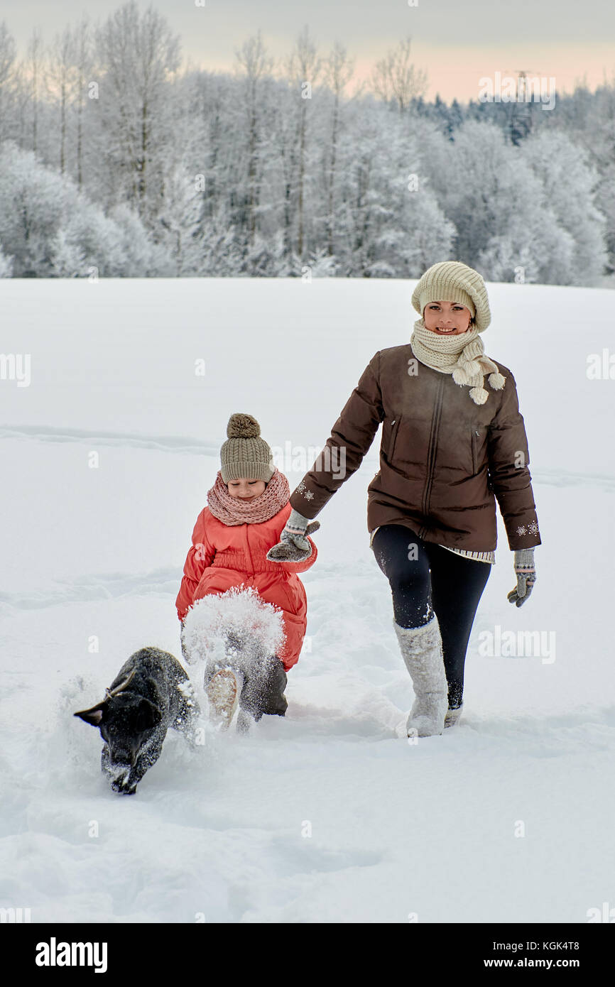Mom with a little daughter spend a day off in the winter forest. They ...