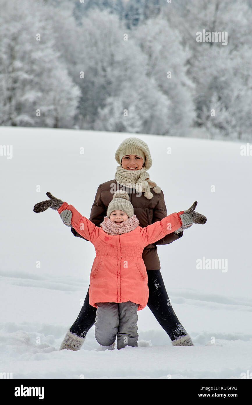 Mom with a little daughter spend a day off in the winter forest. They ...