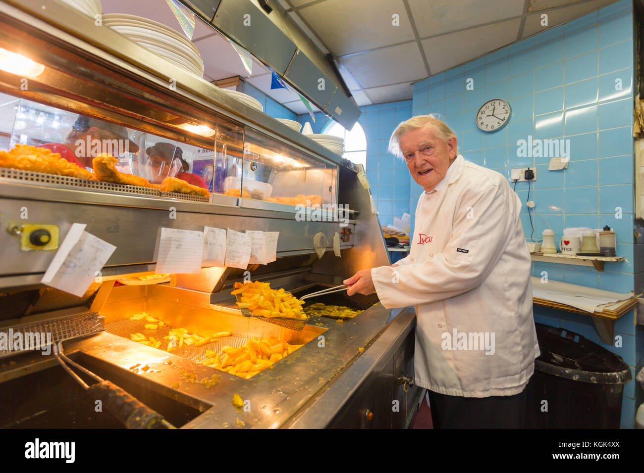 Elderly man working in a traditional English fish and chip shop, UK ...