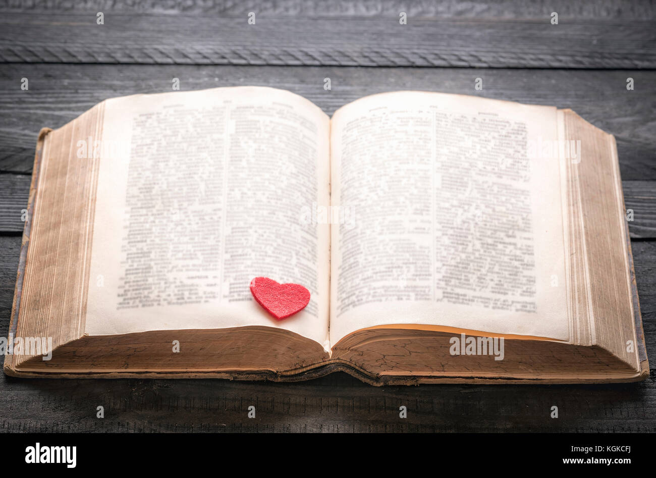 Open old book with a red little heart on its pages, displayed on a ...