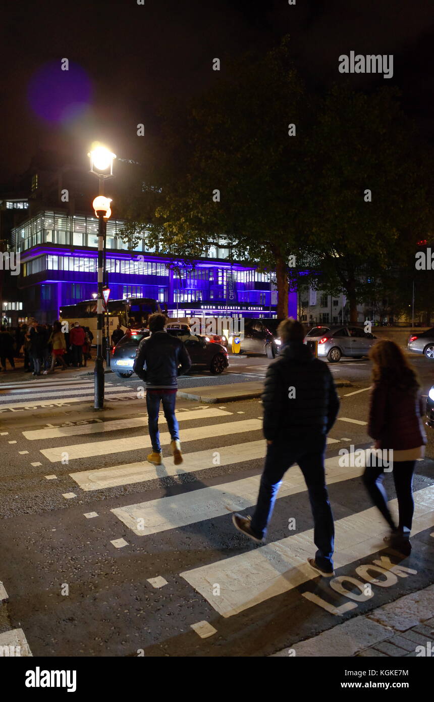 people walking across a zebra crossing at night in London, England ...