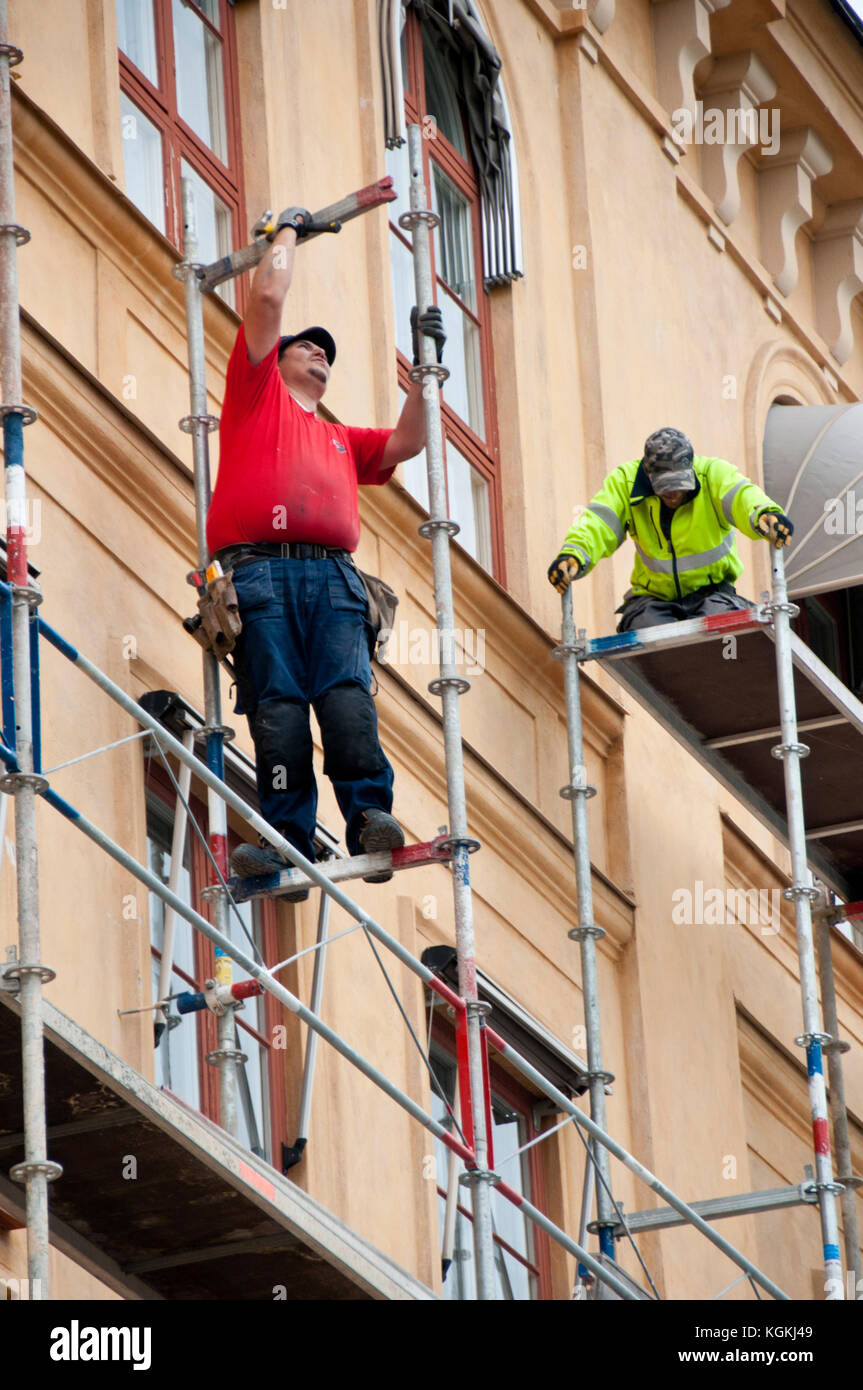 Two men putting up scaffolding without any kind of safety equipment ...