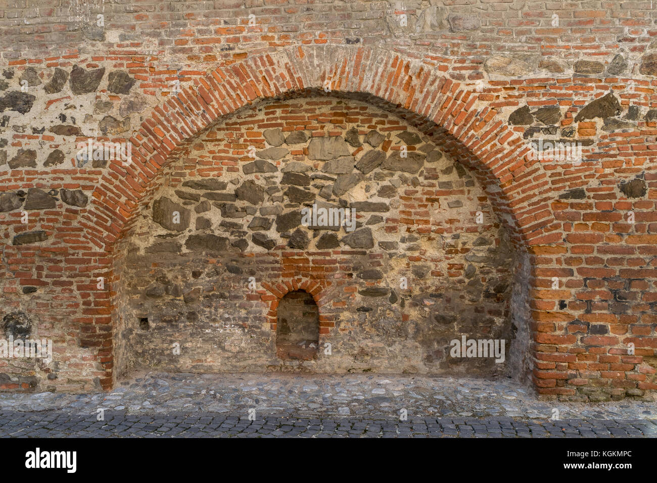 Brick and stone medieval wall with an arch Stock Photo - Alamy