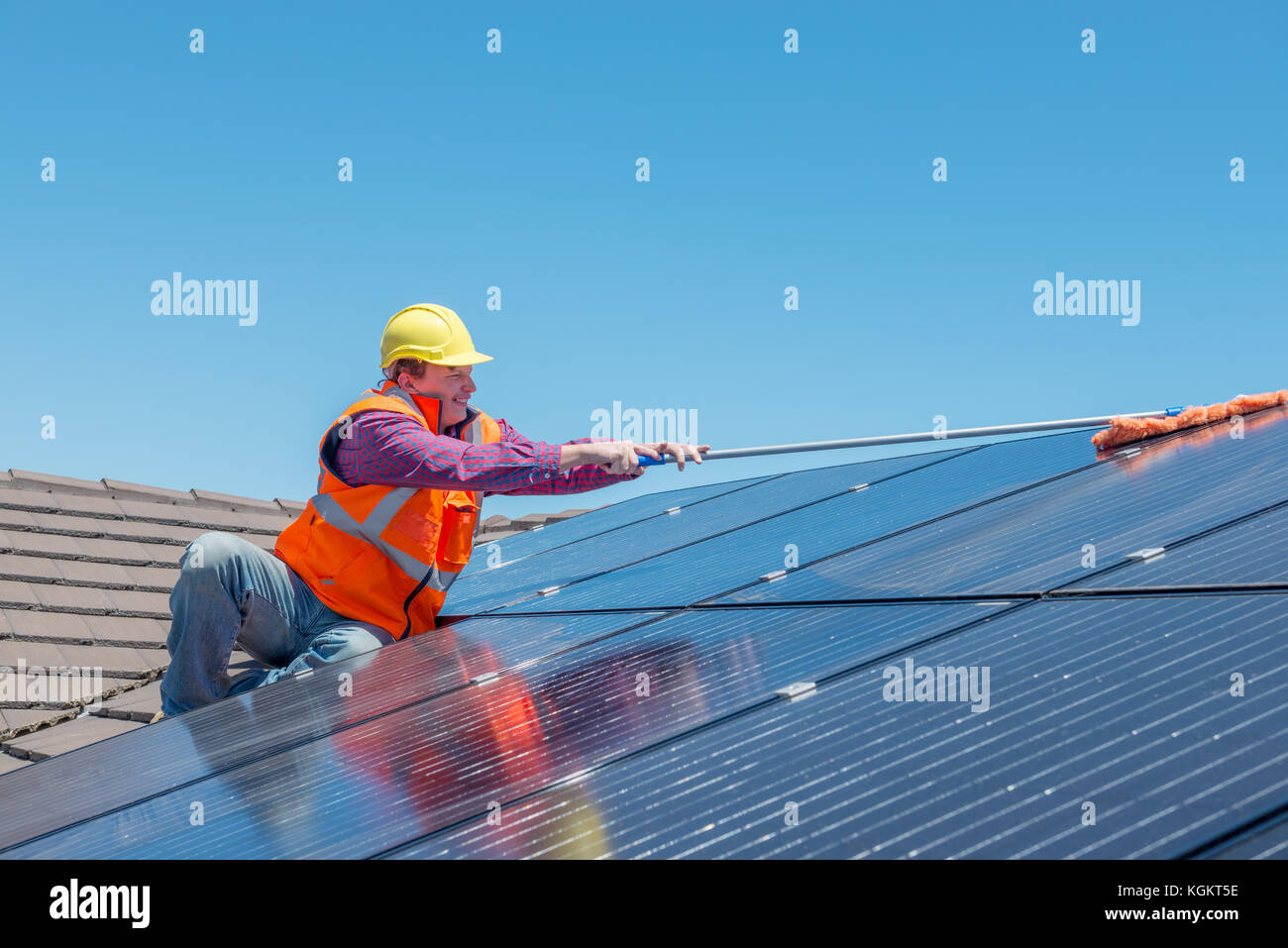 young worker cleaning solar panels on house roof Stock Photo - Alamy