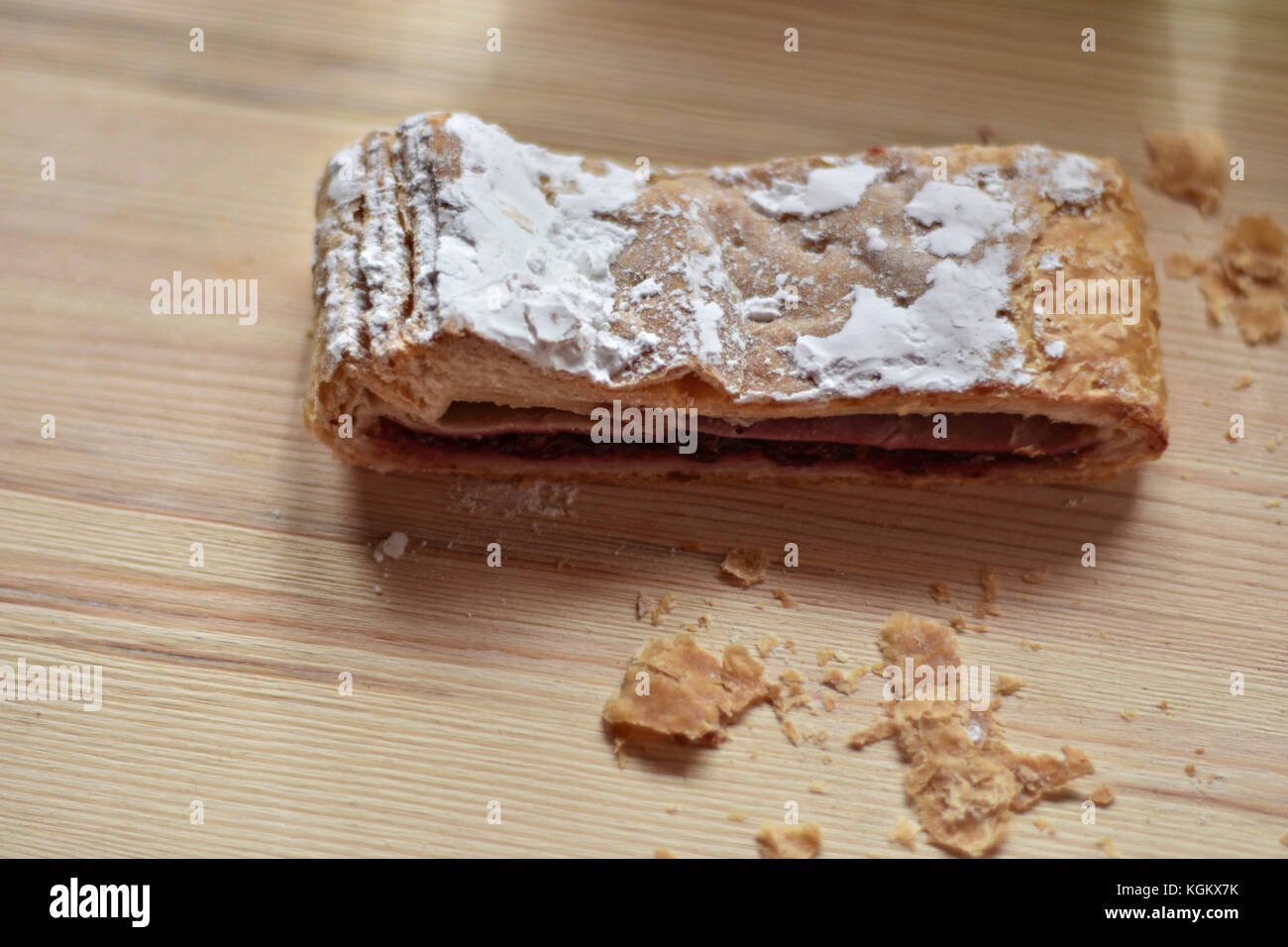 sweet cherry strudel of puff pastry; piece at light wooden table Stock ...