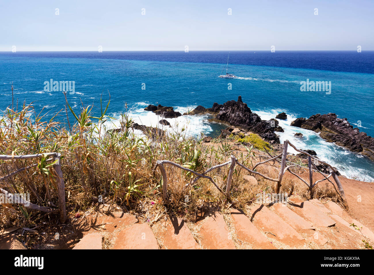 Steps leading down to the ocean with a boat in the background near ...