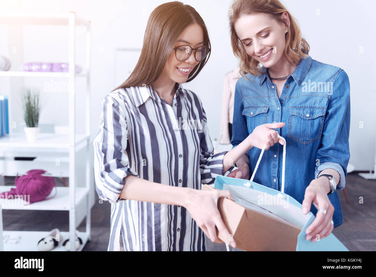 Happy women putting a big box into a gift bag Stock Photo - Alamy