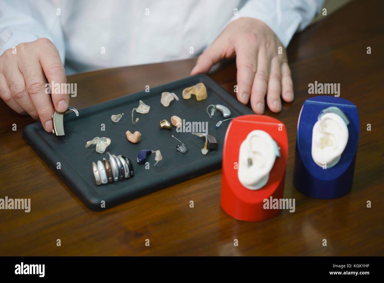 Midsection of audiologist various hearing aids at table in doctor's ...