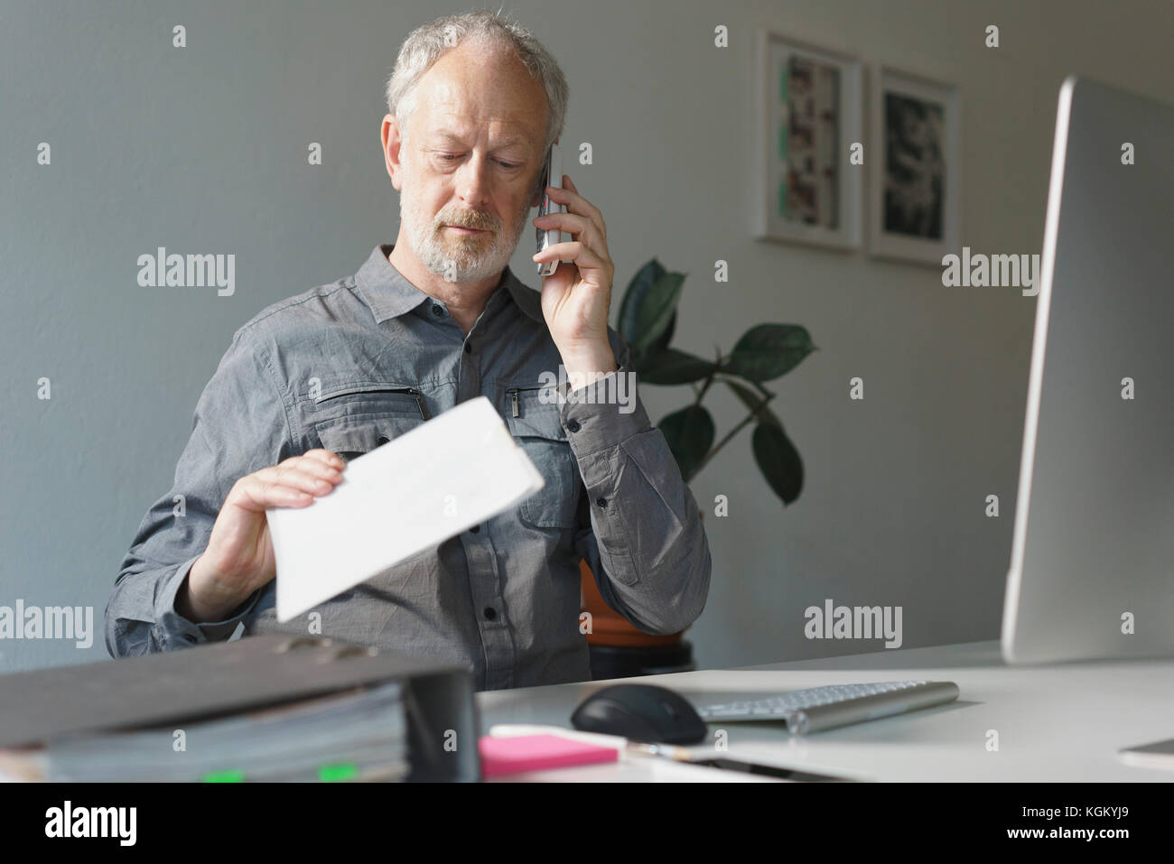 Businessman talking through mobile phone while working at desk in ...