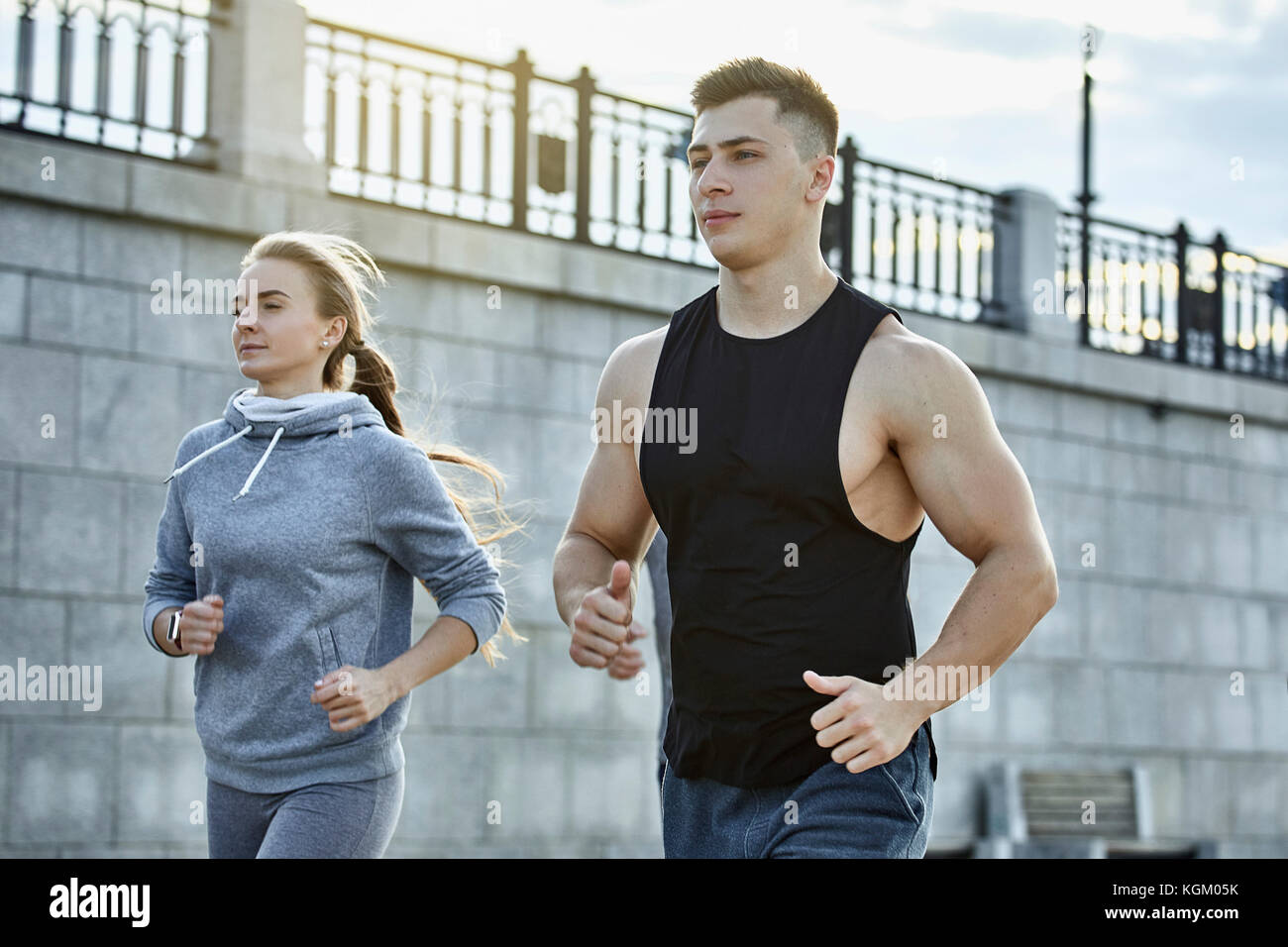 Young male and female athletes jogging against wall Stock Photo - Alamy