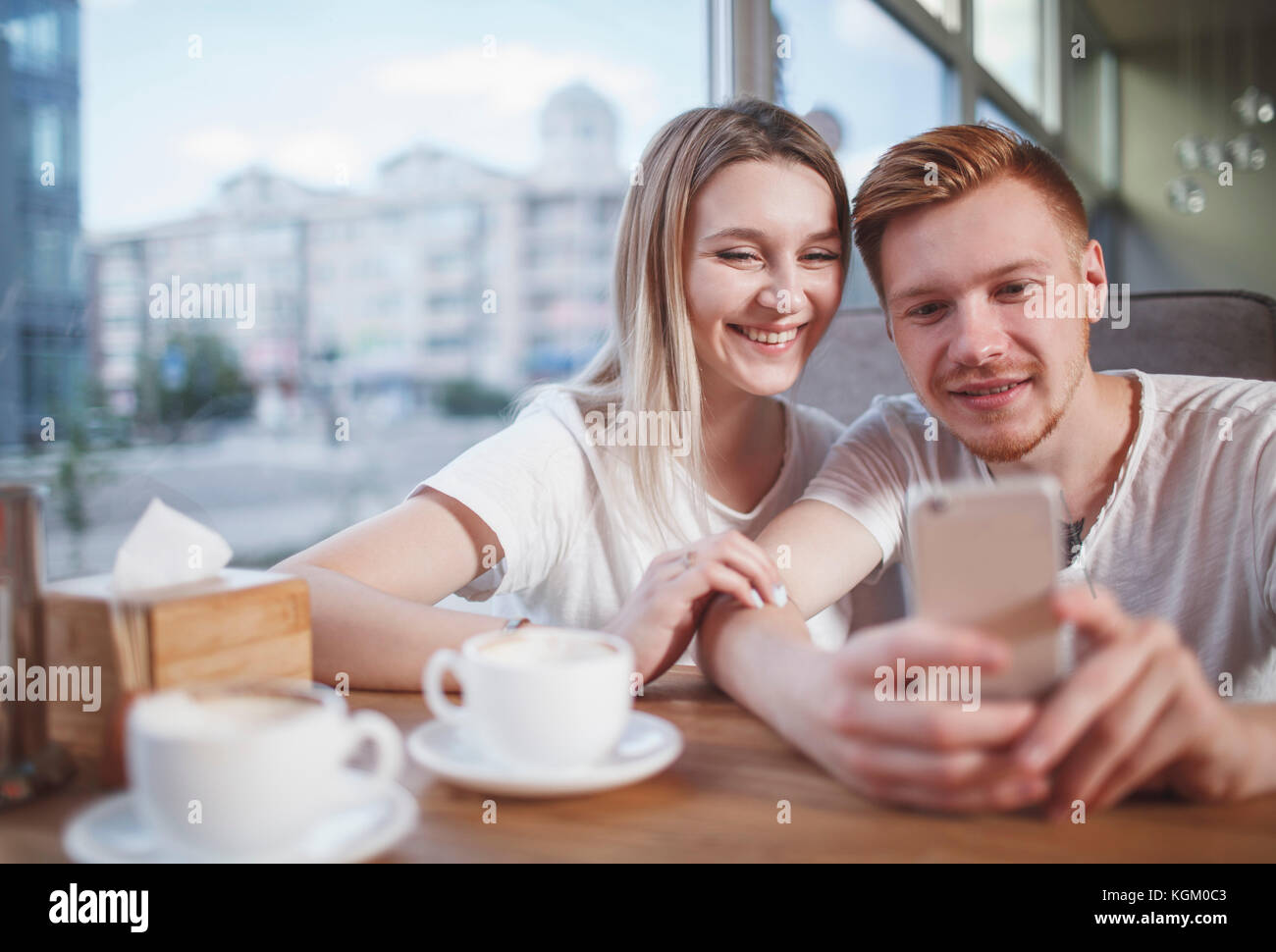 Happy young couple using mobile phone while sitting at restaurant Stock ...