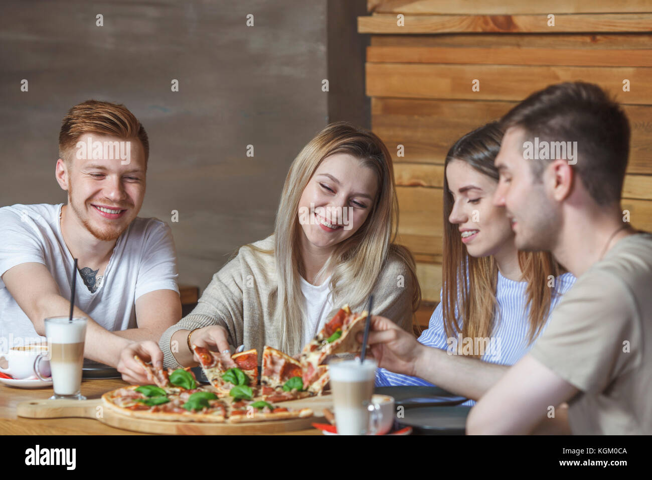 Young friends enjoying pizza at restaurant Stock Photo - Alamy