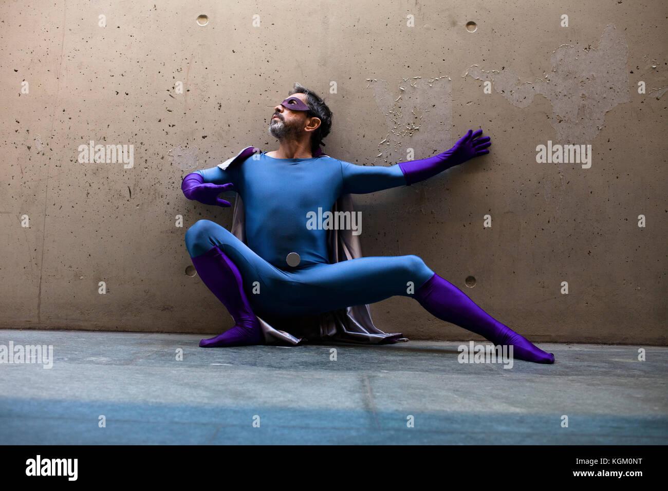 Superhero crouching against wall Stock Photo - Alamy