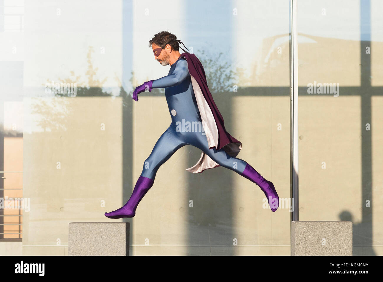 Superhero jumping on concrete against glass wall Stock Photo - Alamy