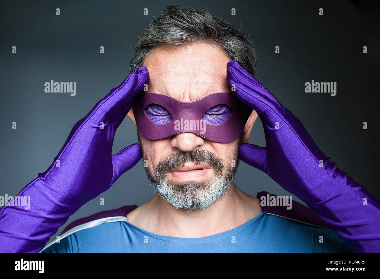 Close-up of superhero with headache against gray background Stock Photo ...