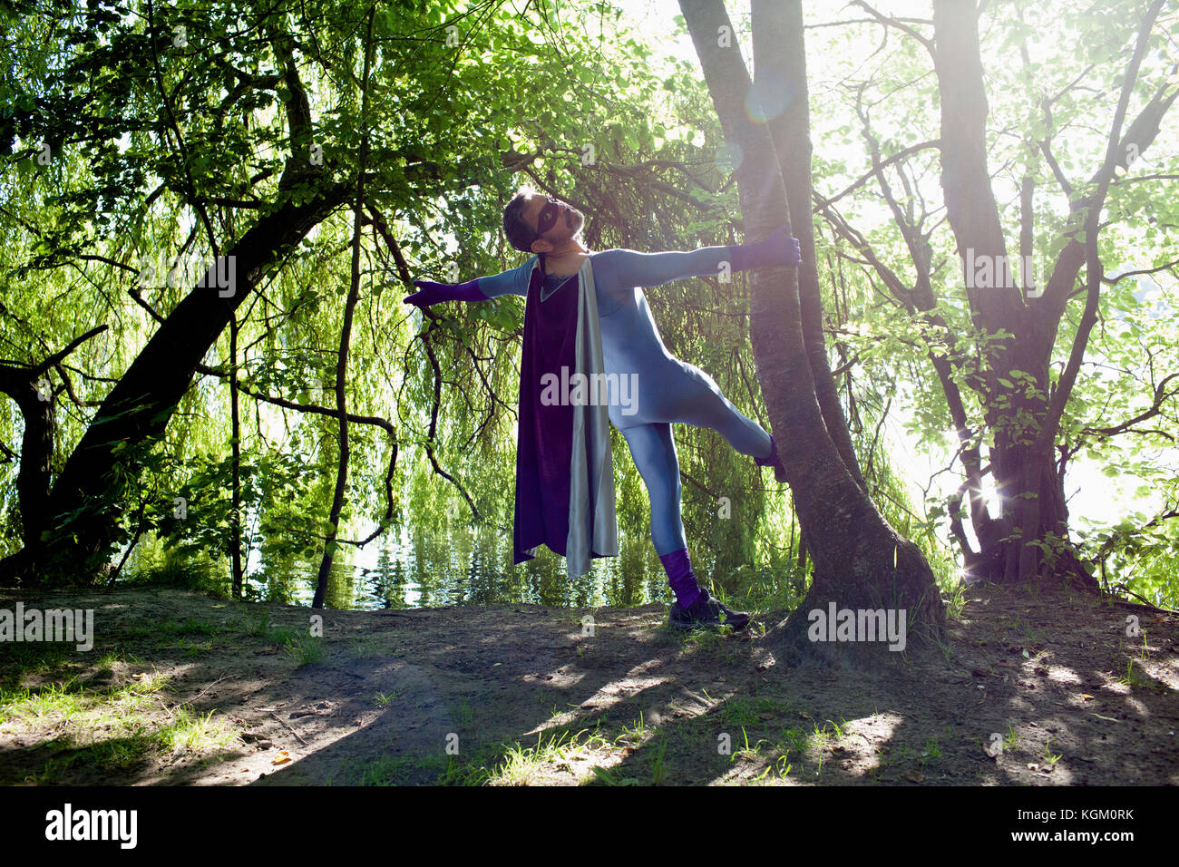 Rear view of superhero standing by tree at riverbank on sunny day Stock ...