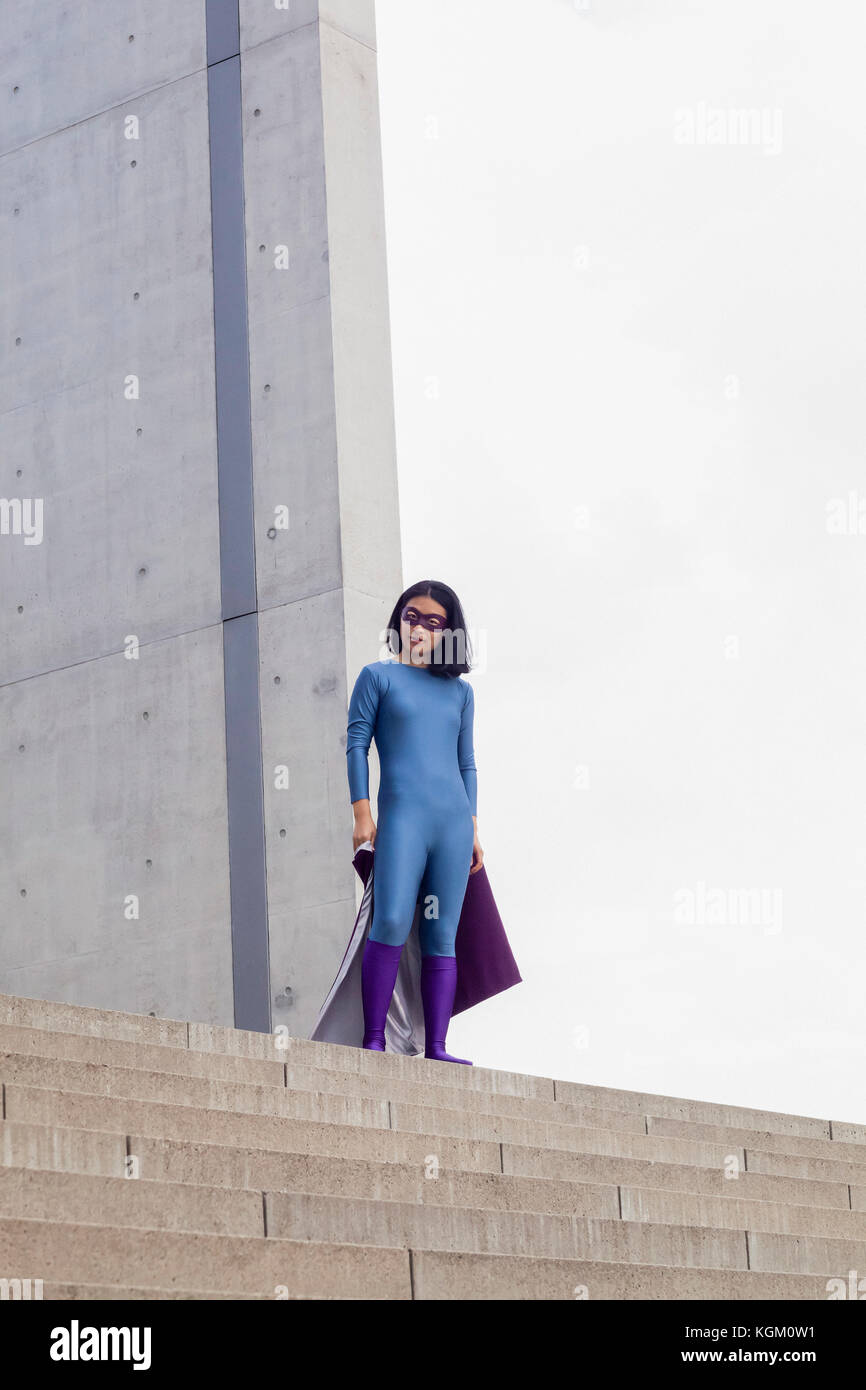 Low angle view of confident female superhero standing on steps against ...