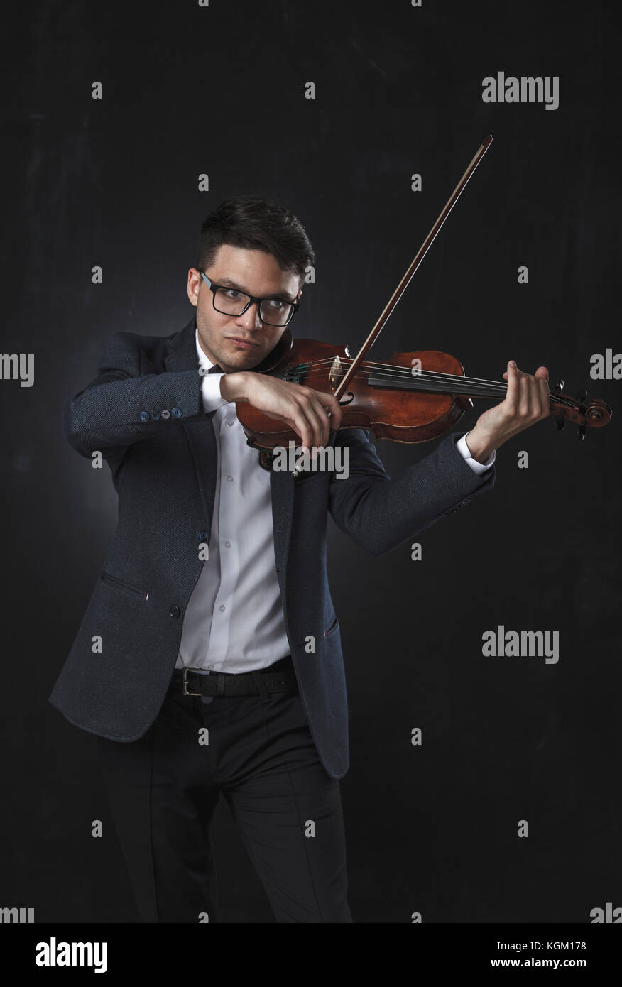 Confident musician playing violin while standing against black ...