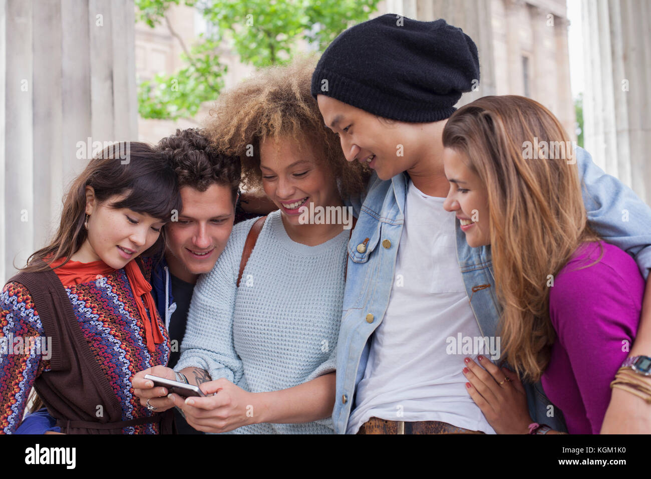 Young woman showing mobile phone to friends Stock Photo - Alamy