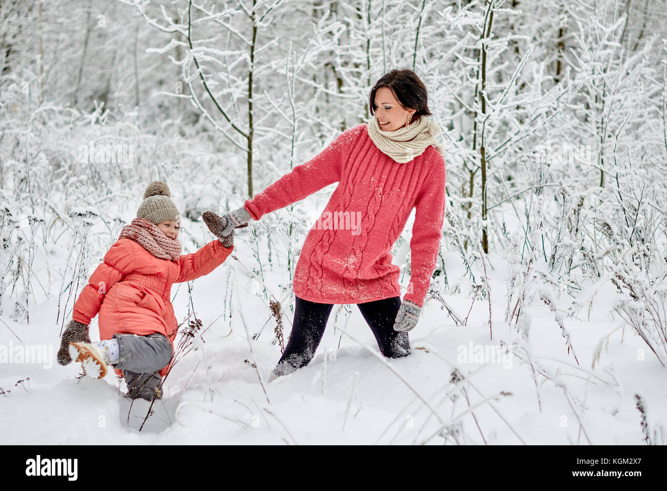 Mom with a little daughter spend a day off in the winter forest. They ...