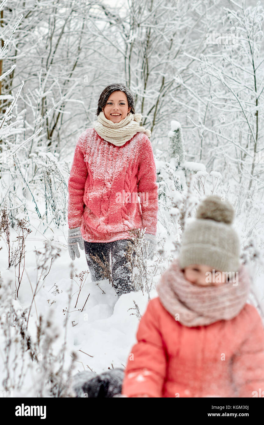 Mom with a little daughter spend a day off in the winter forest. They ...