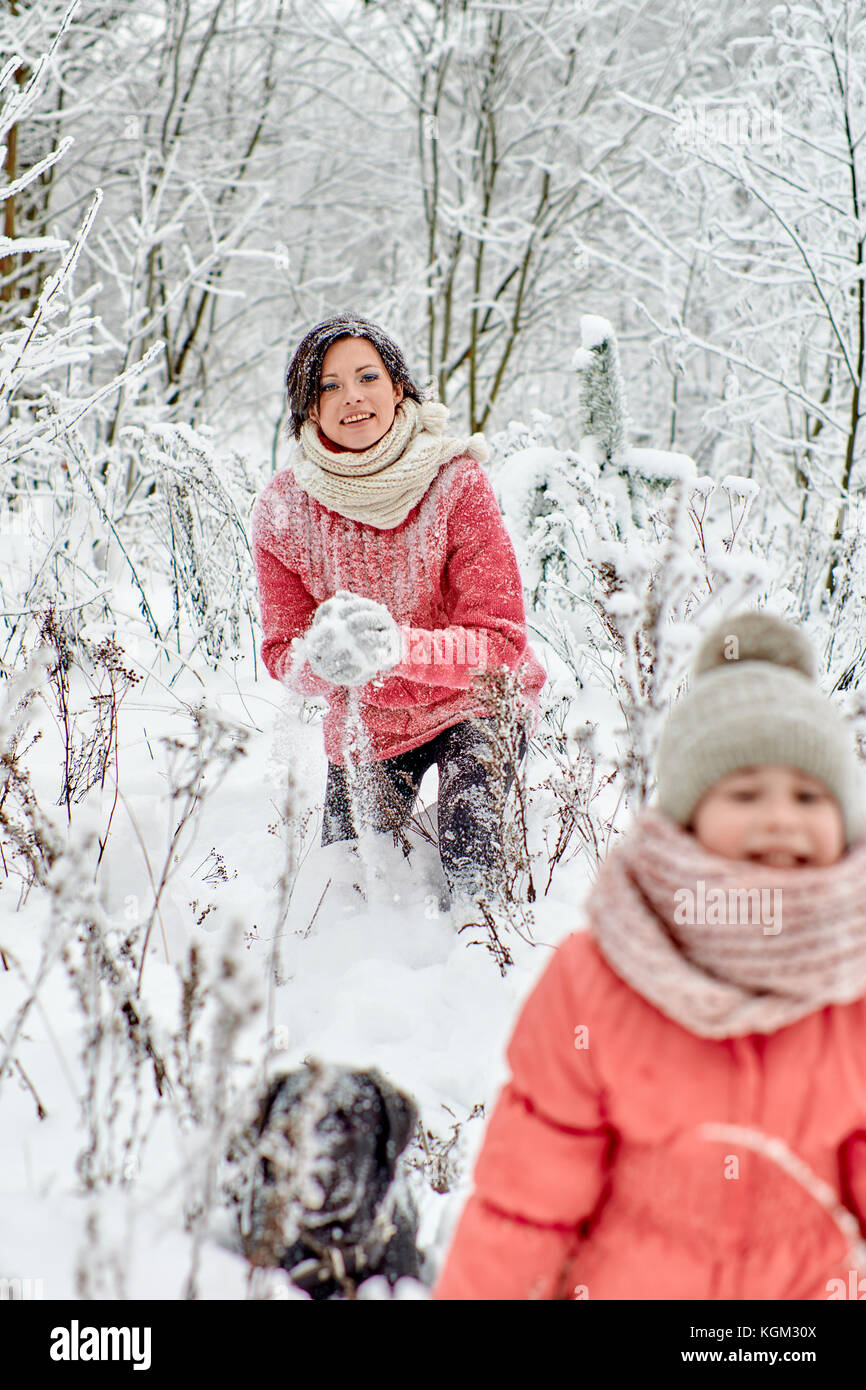 Mom with a little daughter spend a day off in the winter forest. They ...