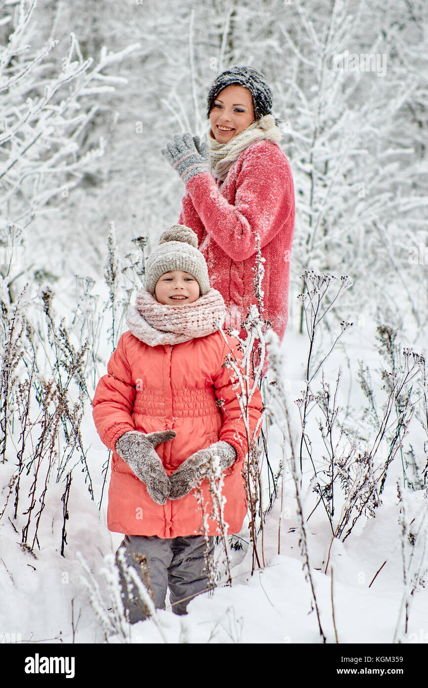 Mom with a little daughter spend a day off in the winter forest. They ...