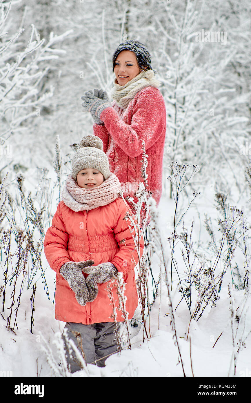 Mom with a little daughter spend a day off in the winter forest. They ...