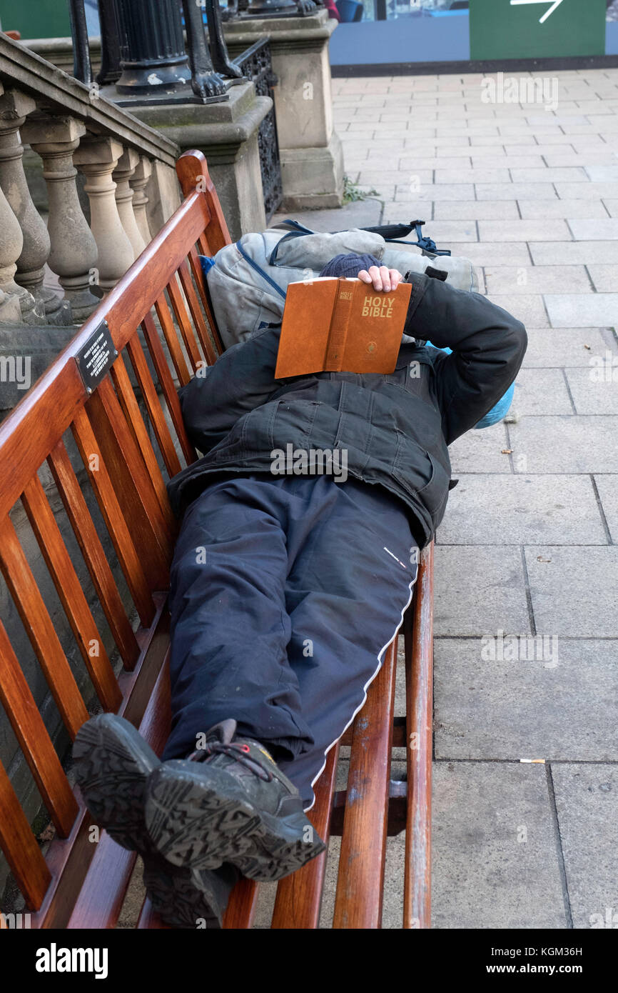 A Homeless man in Edinburgh relaxing on a public bench reading The ...