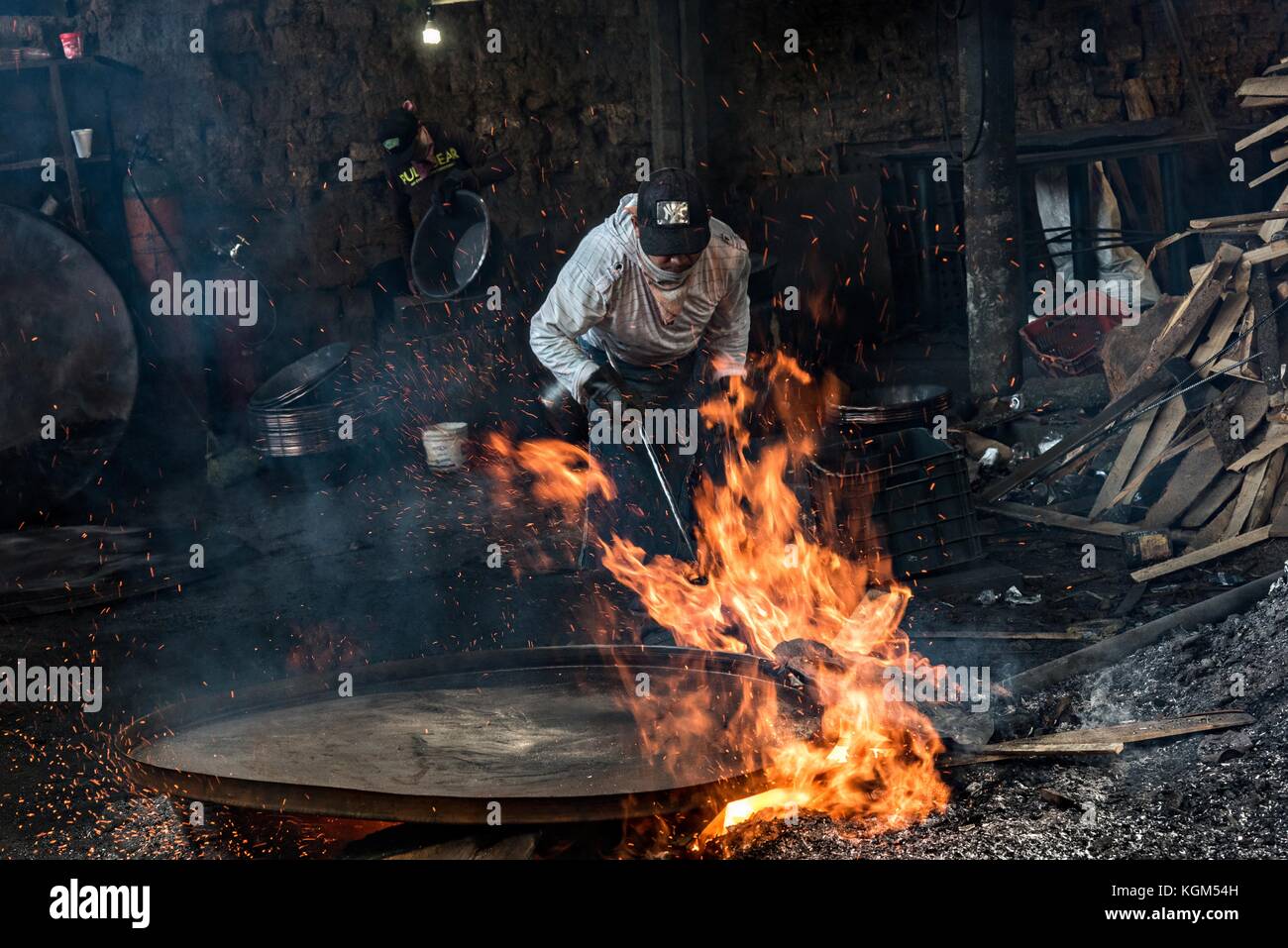 An indigenous Purepecha worker places a copper pan on an open forge to ...