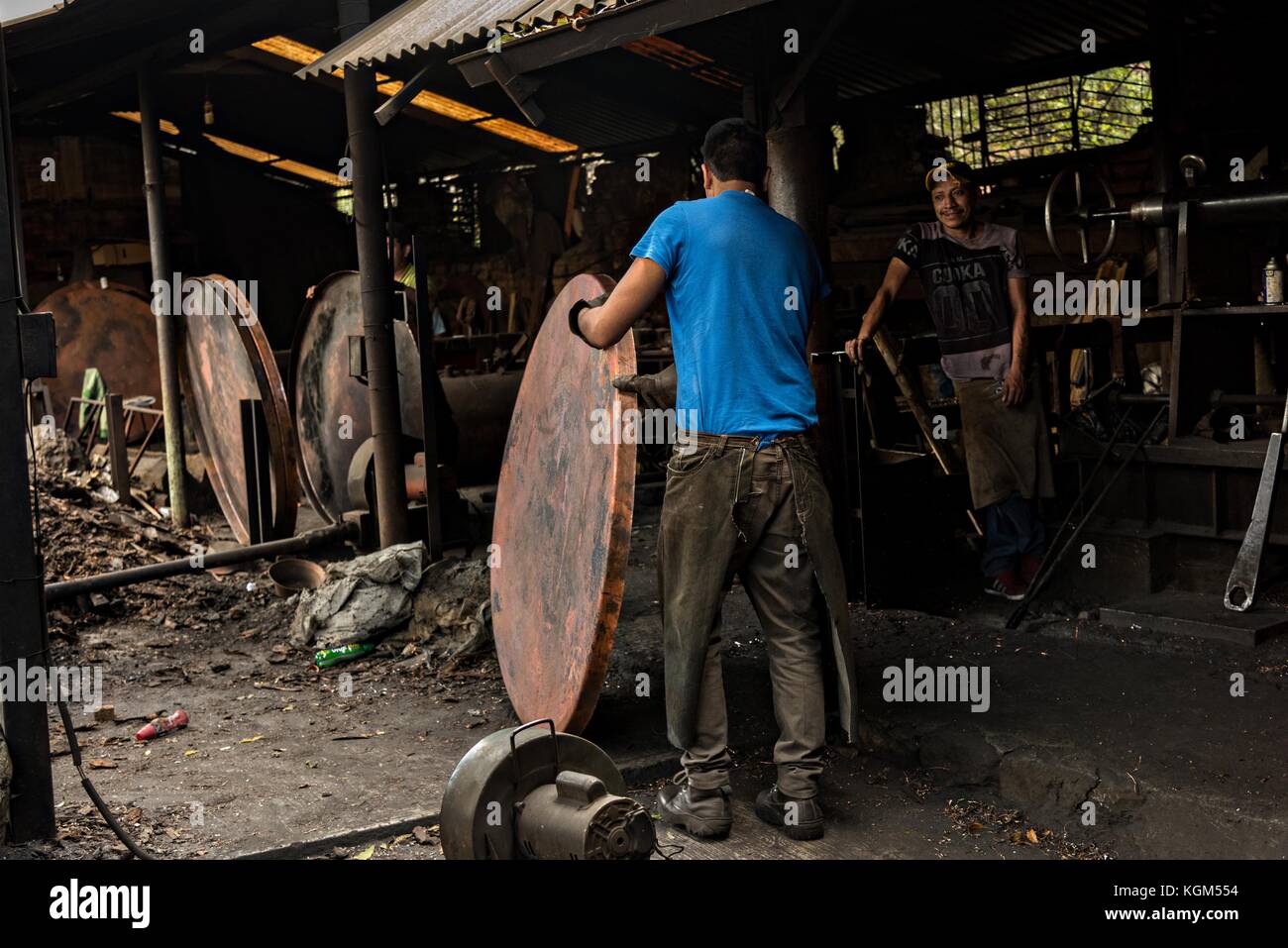 An indigenous Purepecha worker moves a copper pot bottom to another ...