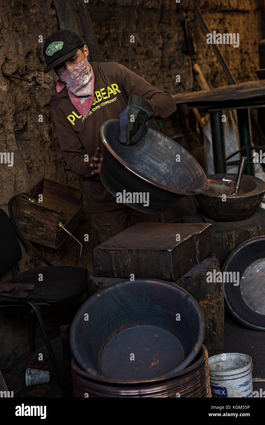 An indigenous Purepecha worker checks a copper pan for defects at a ...